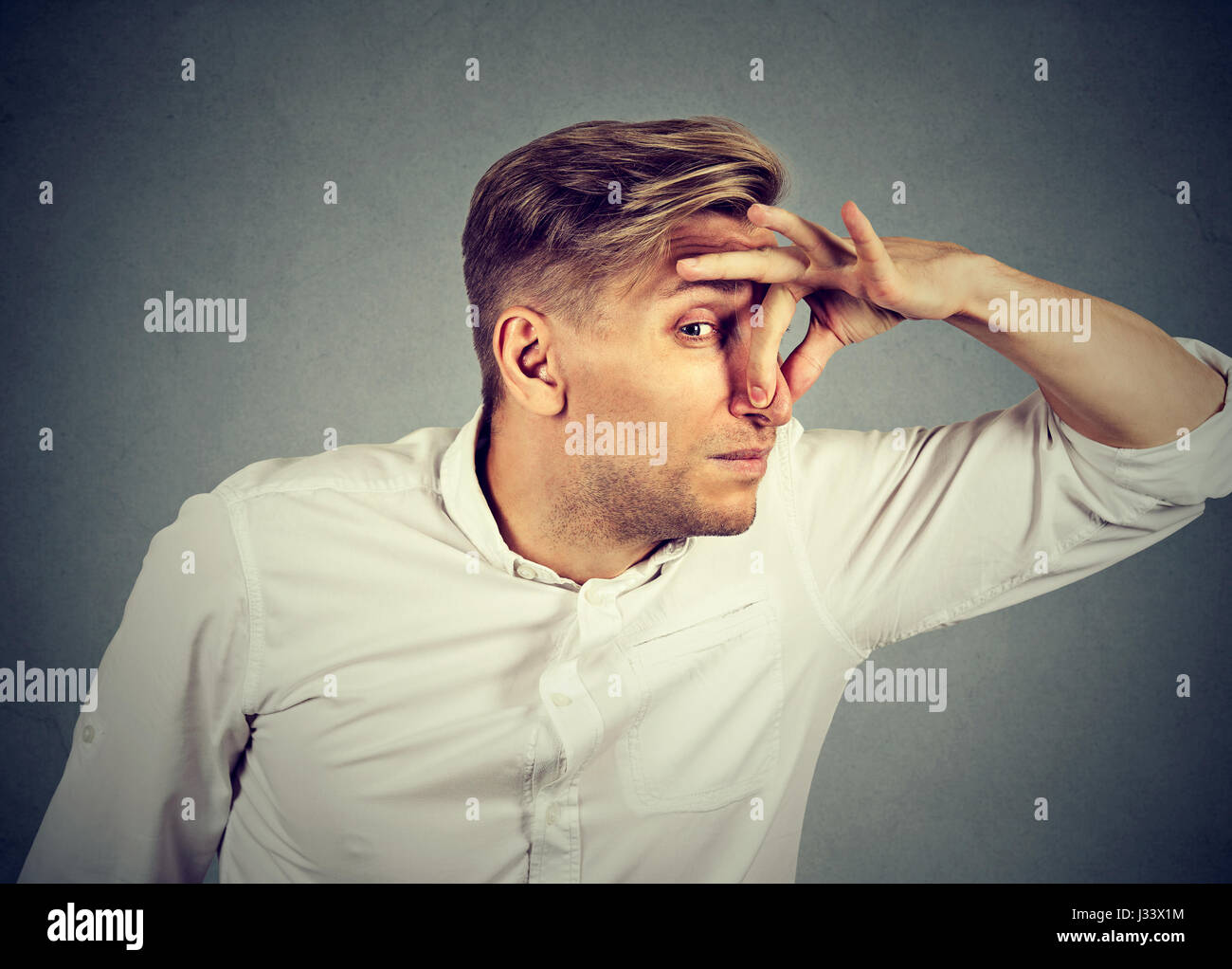 man pinches nose with fingers looks with disgust something stinks bad ...