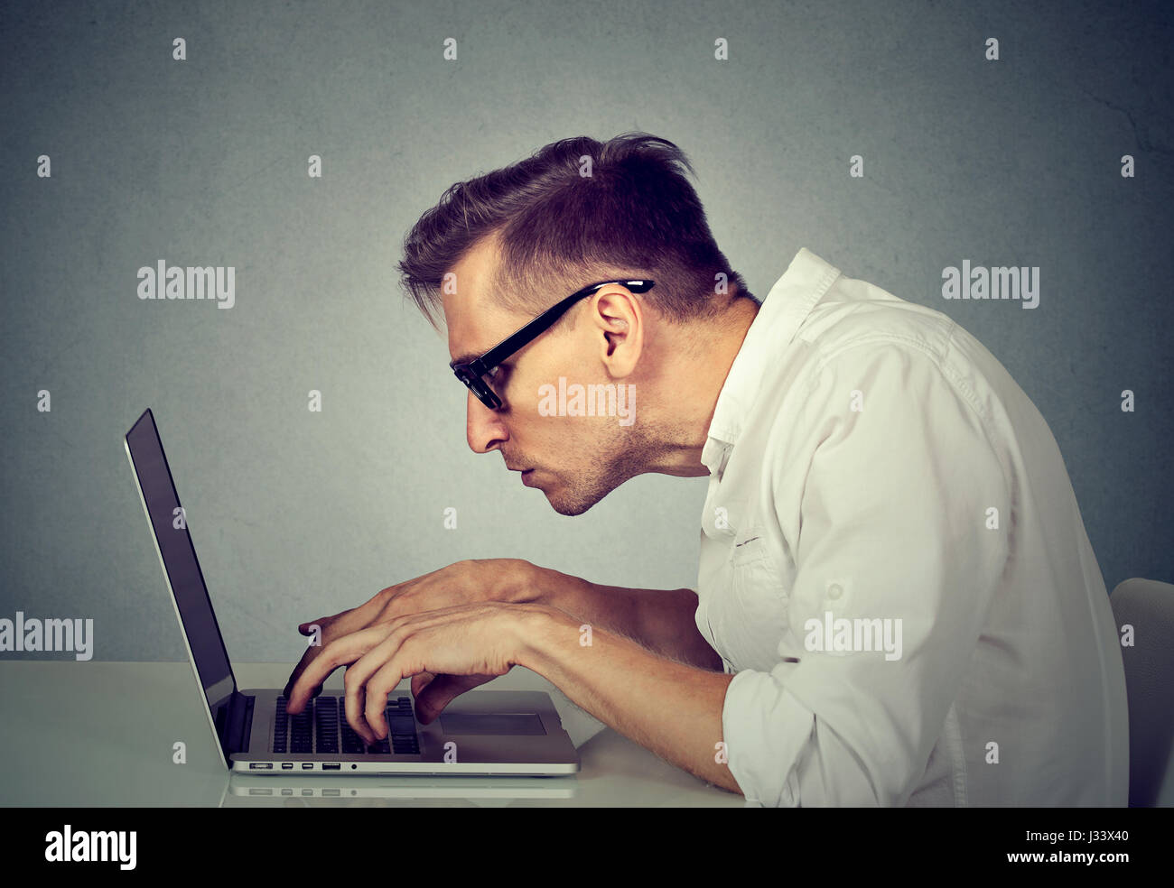 Side profile young man in glasses working on computer sitting at desk ...