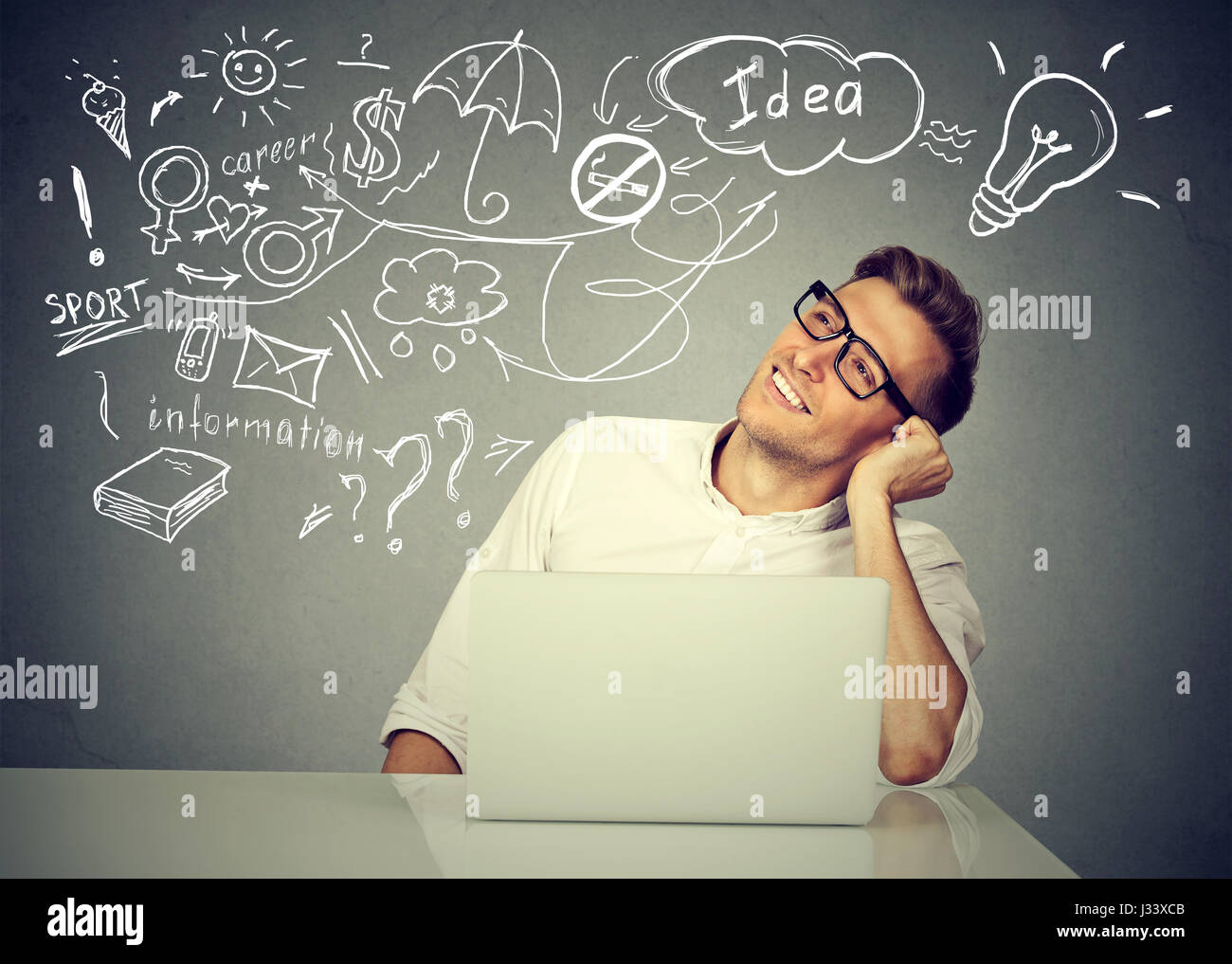 Closeup portrait happy young man working on computer thinking dreaming ...