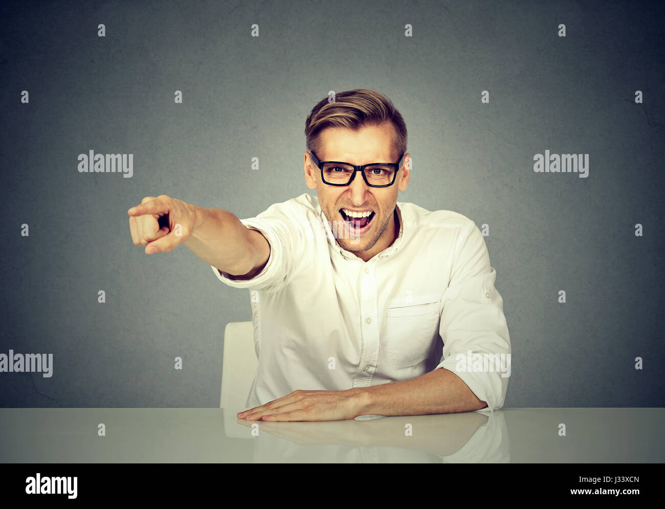 Angry businessman sitting at his desk and screaming Stock Photo - Alamy