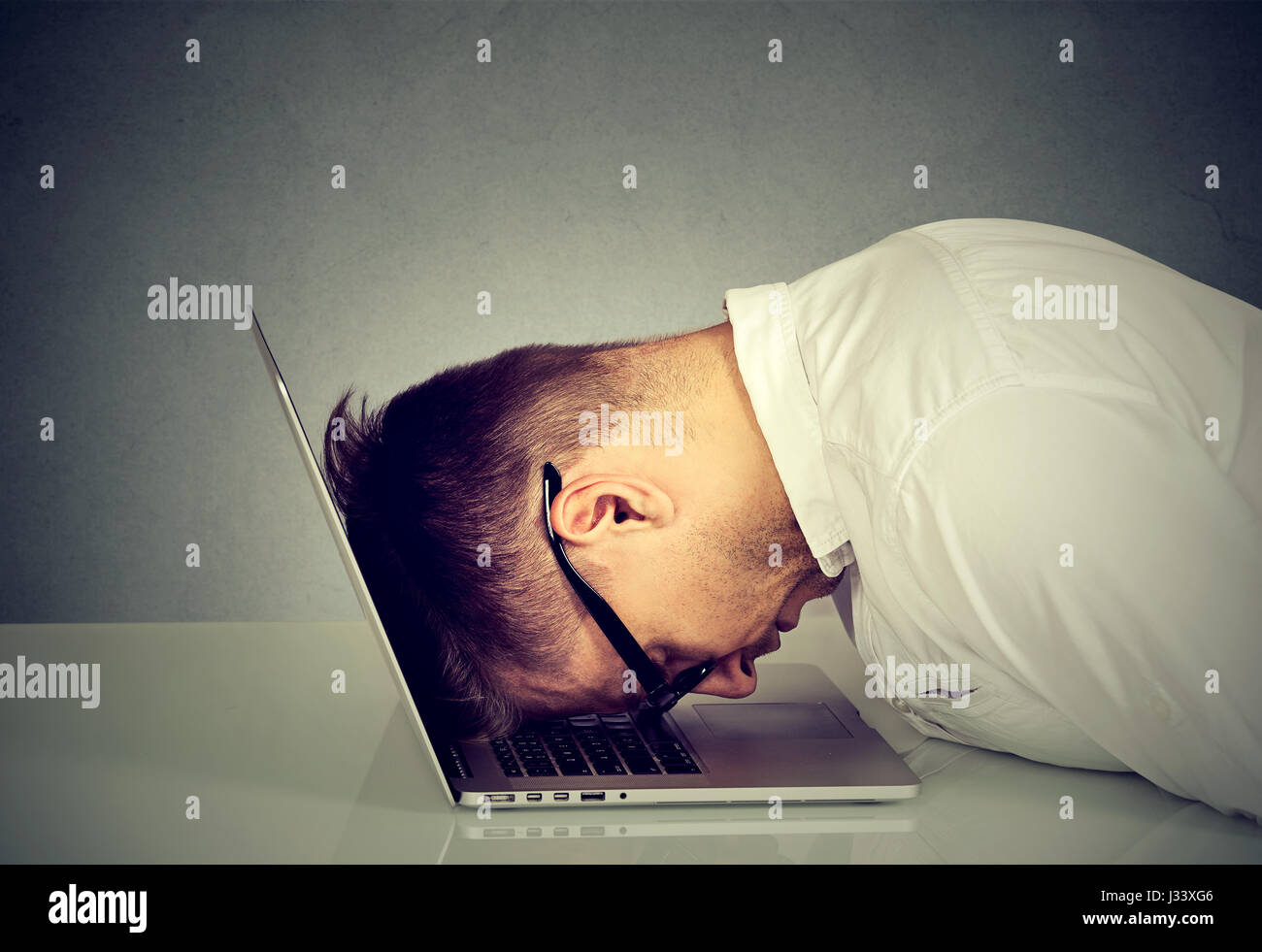 Desperate employee, stressed young man resting head on laptop keyboard ...