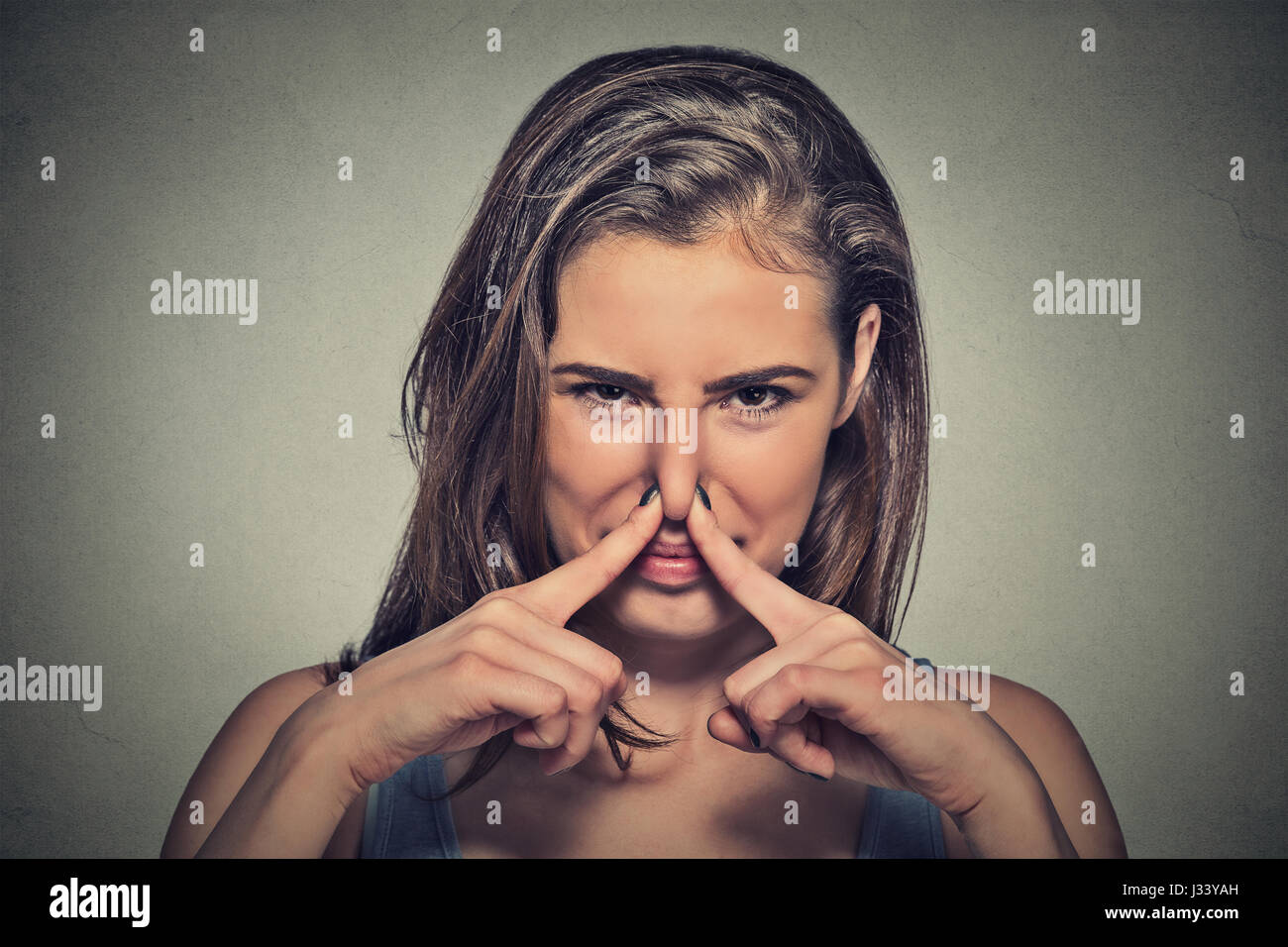 Closeup portrait headshot woman pinches nose with fingers hands looks ...