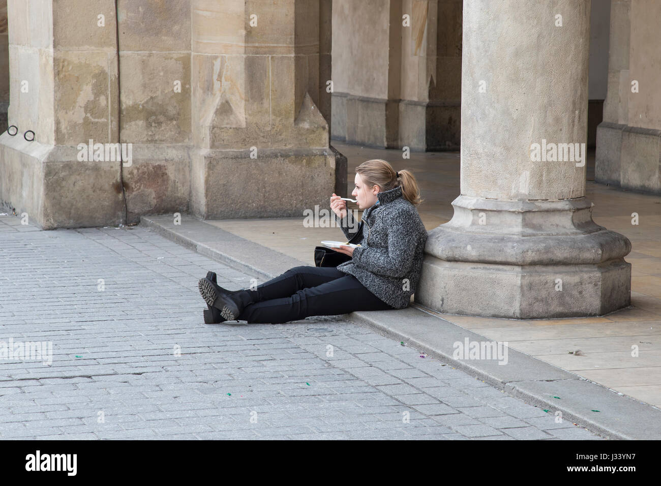 Young girl sitting in market square eating a snack Stock Photo - Alamy