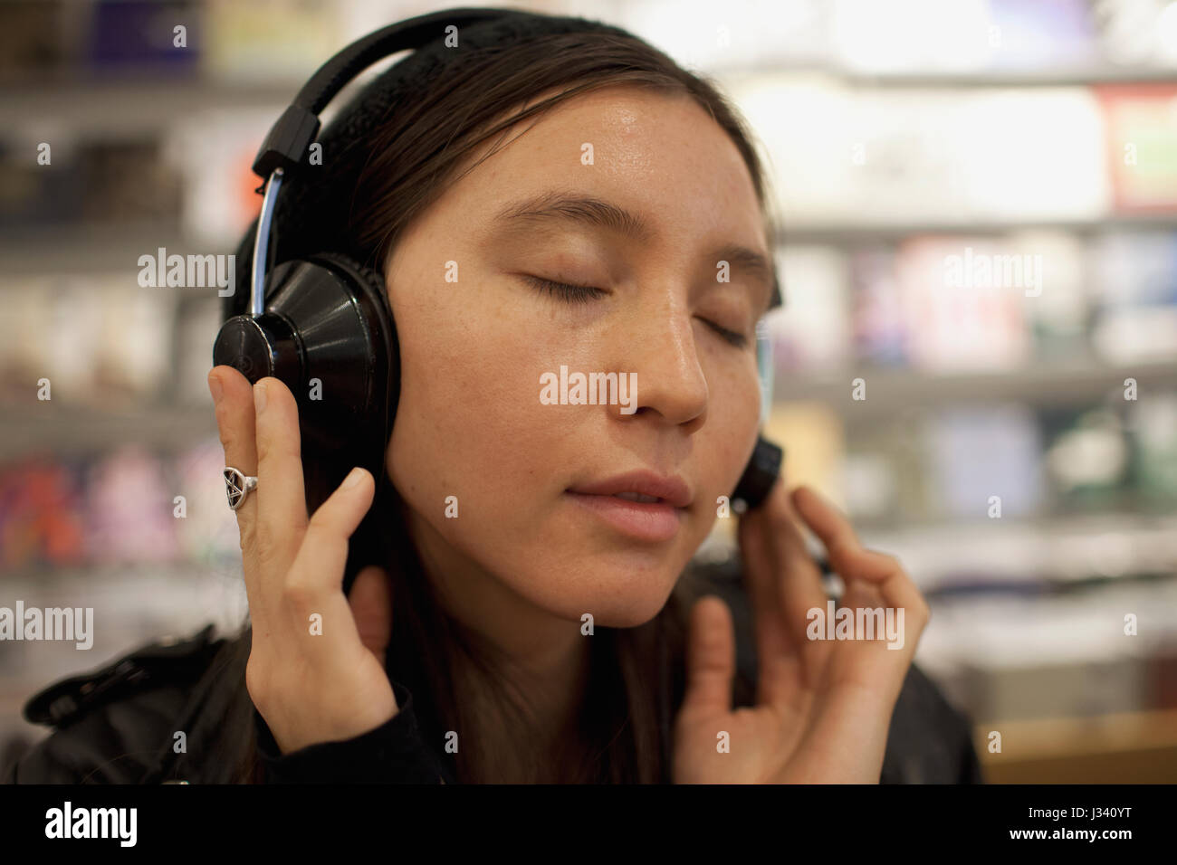 Young woman listening to music in a record store Stock Photo - Alamy