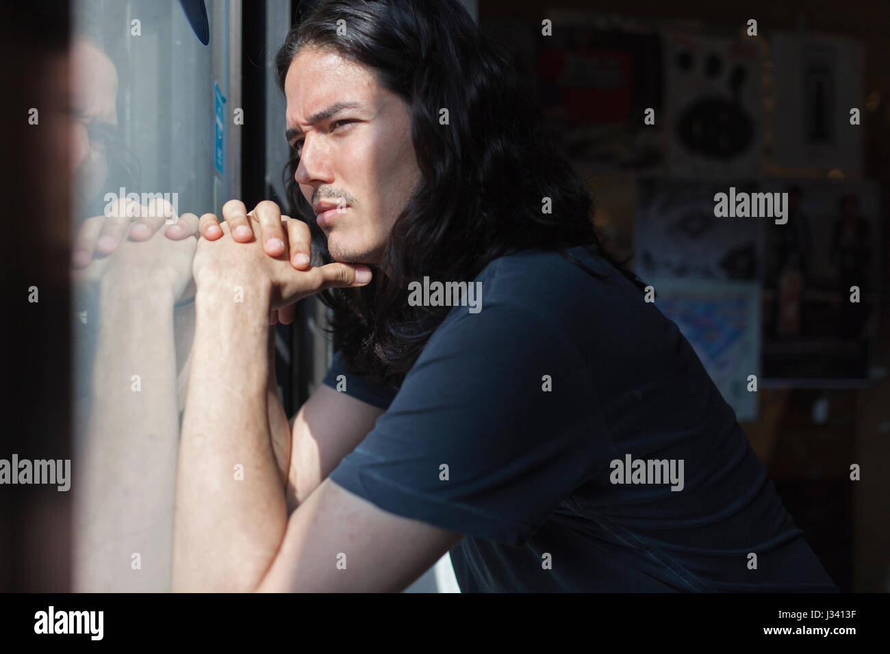 Portrait of a young man looking through a window Stock Photo - Alamy