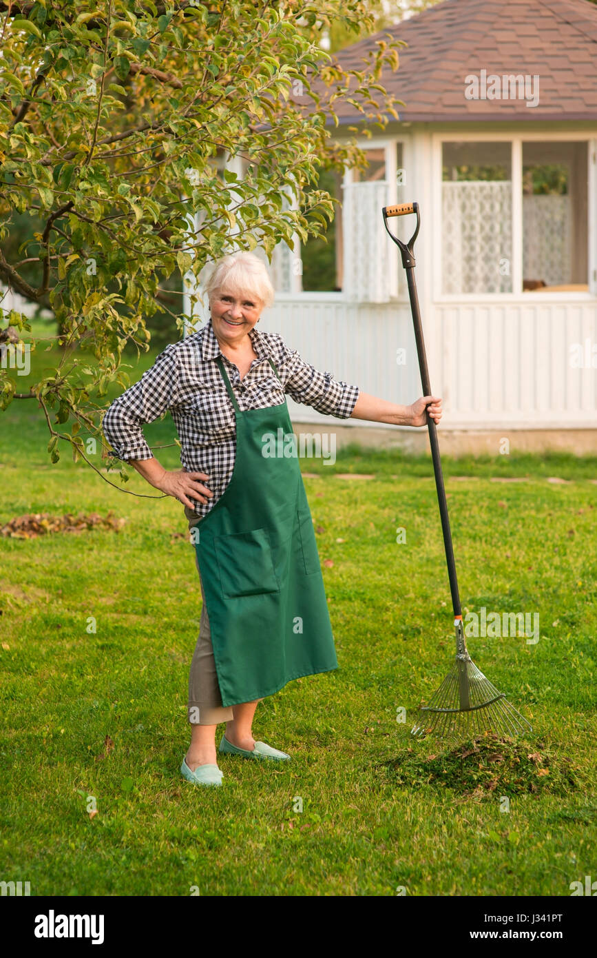 Senior woman with rake smiling Stock Photo - Alamy