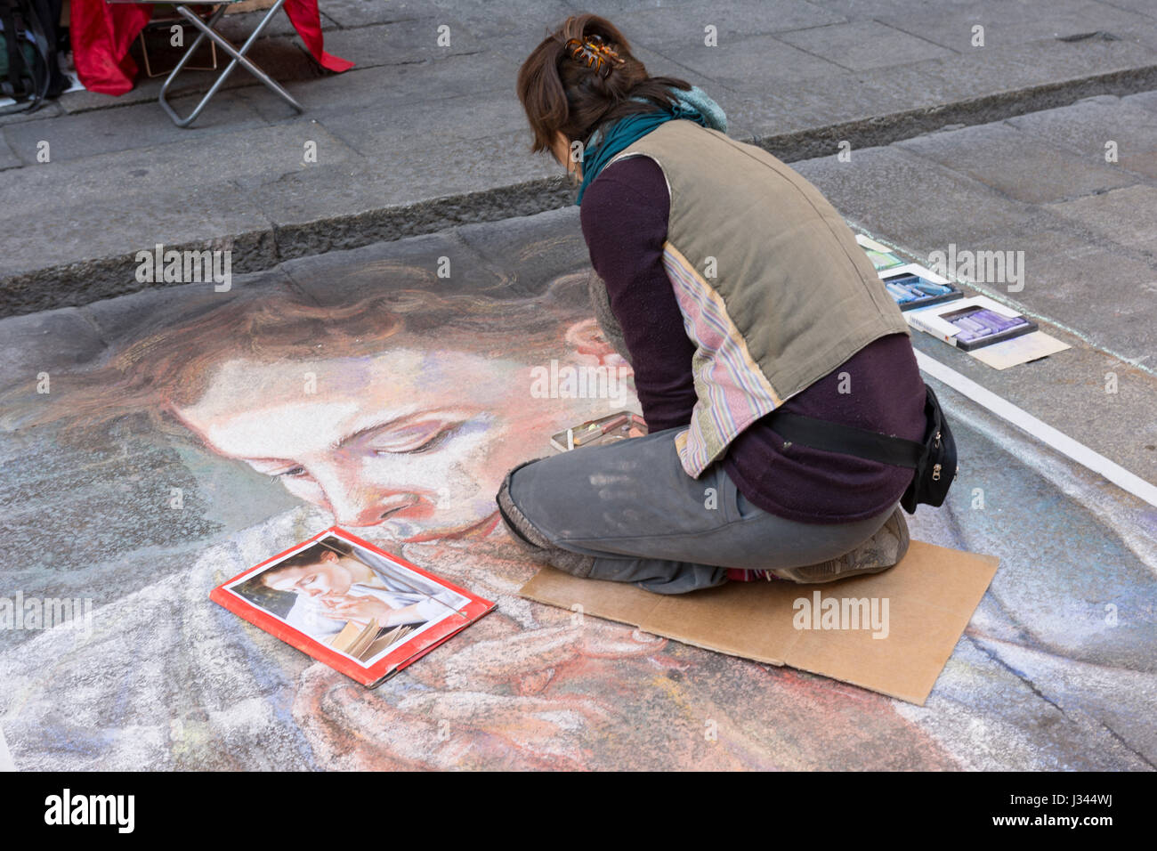 a young street artist while drawing with chalk on the pavement Stock ...