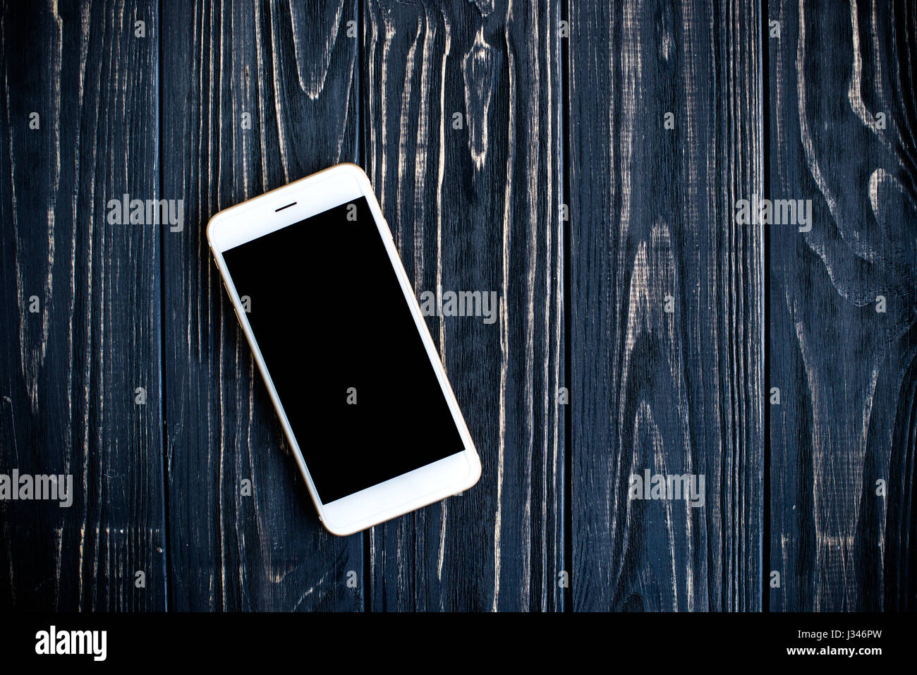 White isolated screen smartphone mock-up on black wooden table board ...