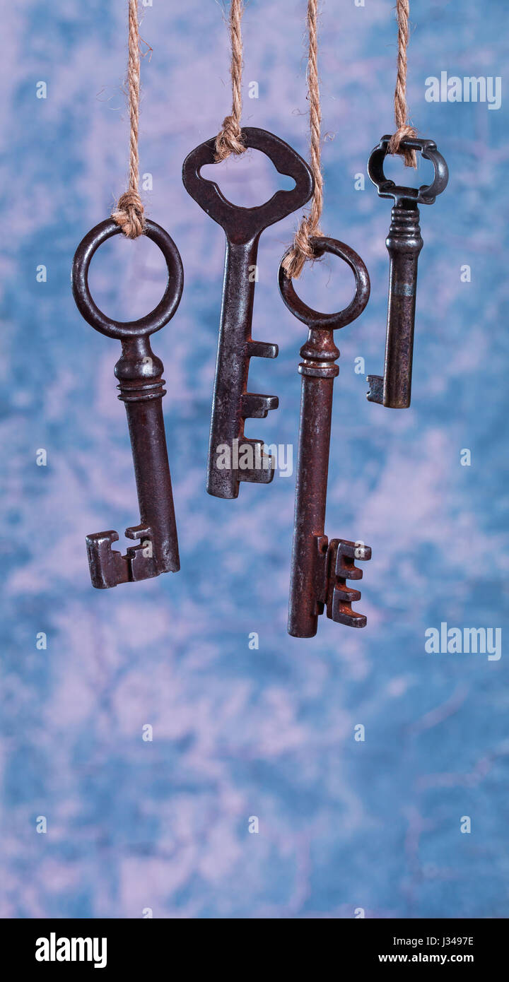 Four old keys hanging on blue Stock Photo - Alamy