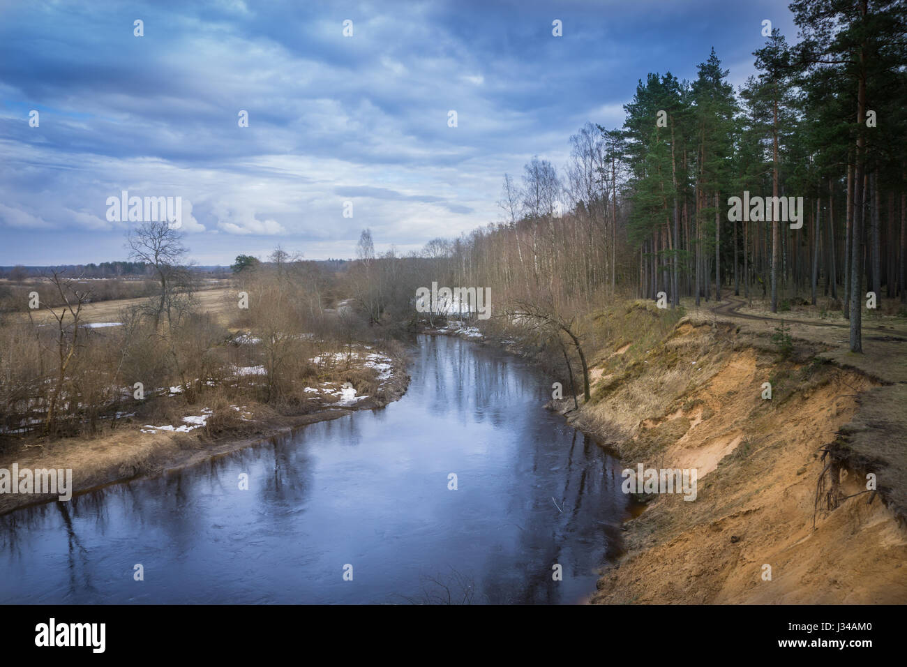 Latvian river with its bend in spring, with reflection of the sky and ...