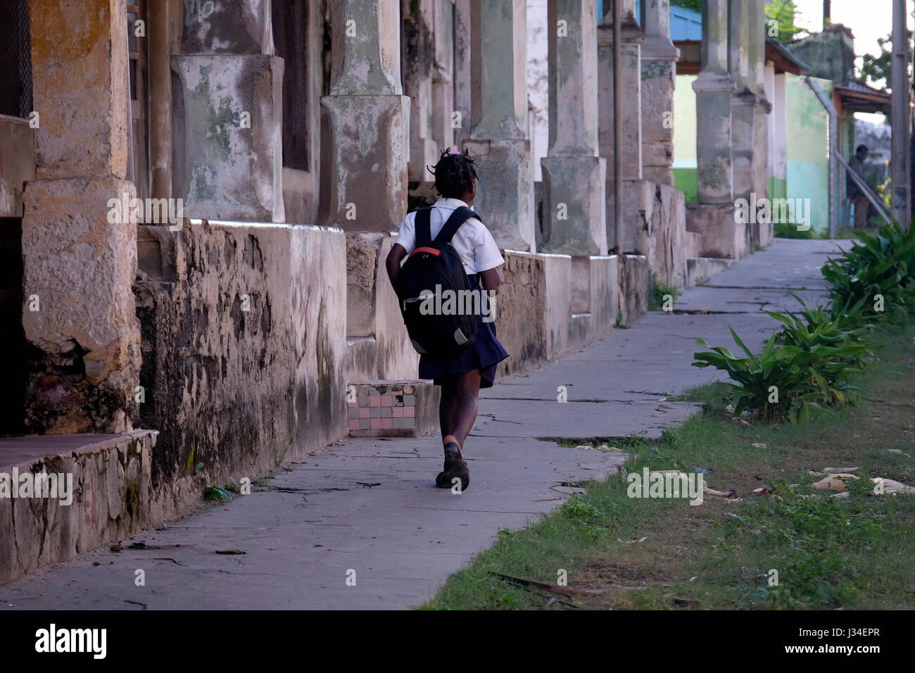 A young schoolgirl walking along an old Portuguese colonial building in ...