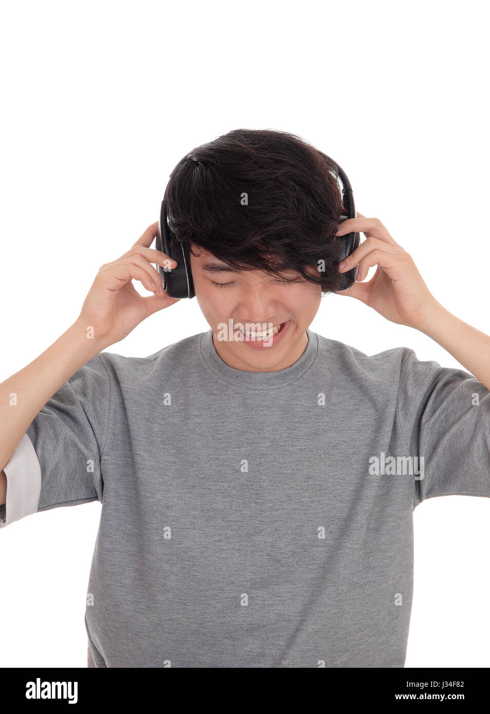 A young handsome Korean teenager listen to music with his headset, in a ...