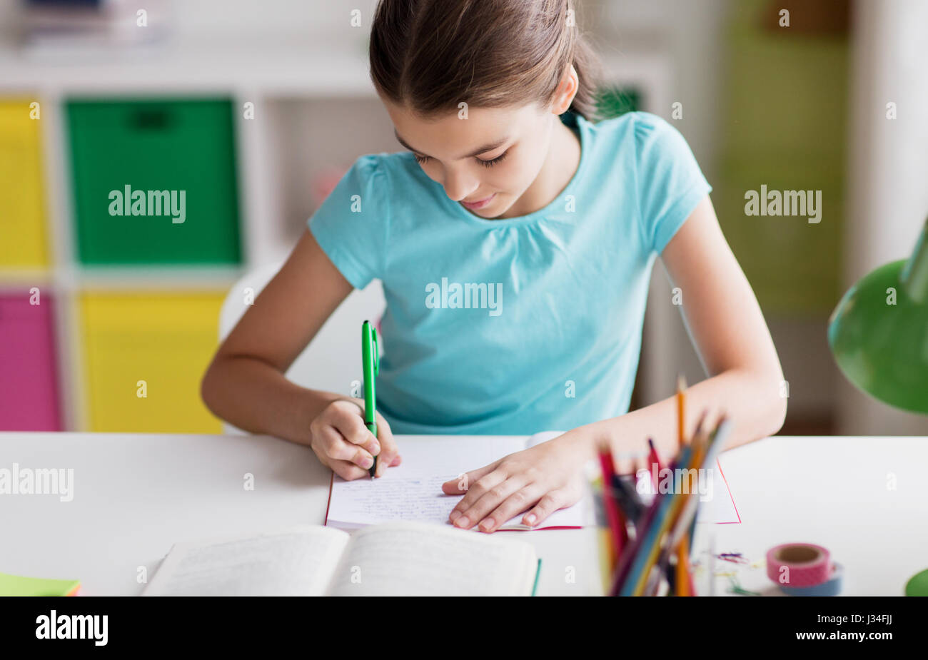 happy girl with book writing to notebook at home Stock Photo - Alamy