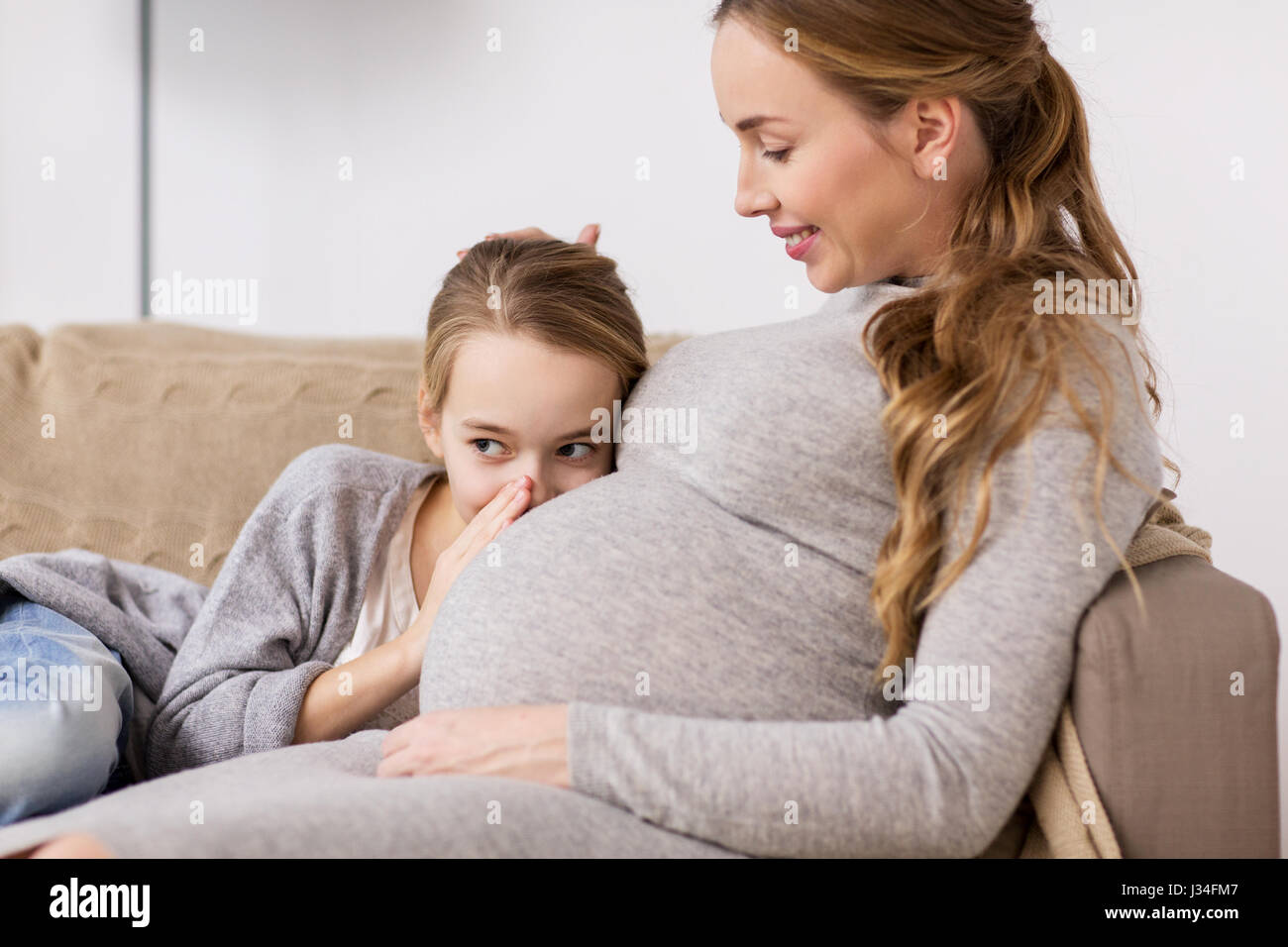 pregnant woman and girl talking to baby in belly Stock Photo - Alamy