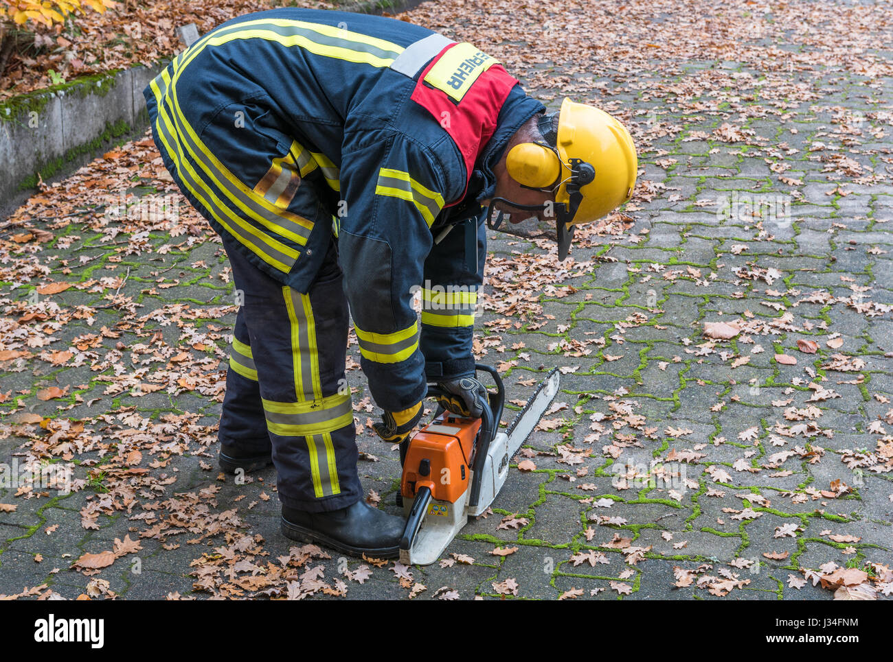 German Fireman in action outdoors with chainsaw Stock Photo - Alamy