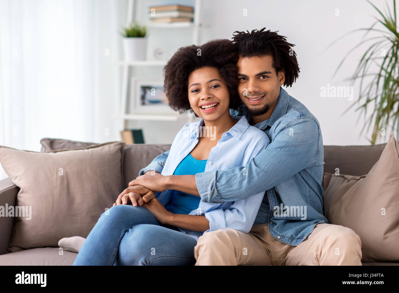 happy couple sitting on sofa and hugging at home Stock Photo - Alamy