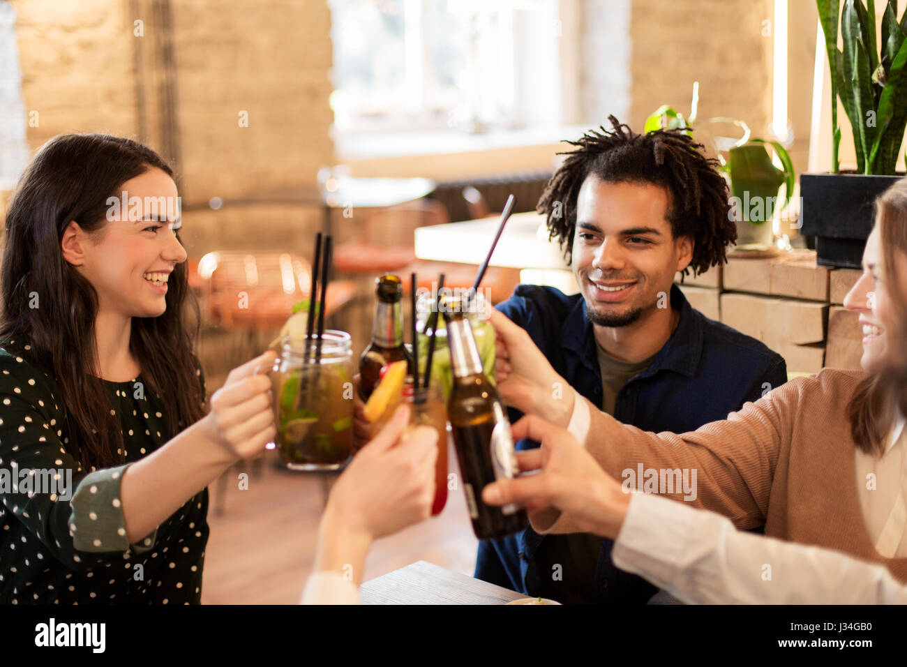 happy friends clinking drinks at bar or cafe Stock Photo - Alamy