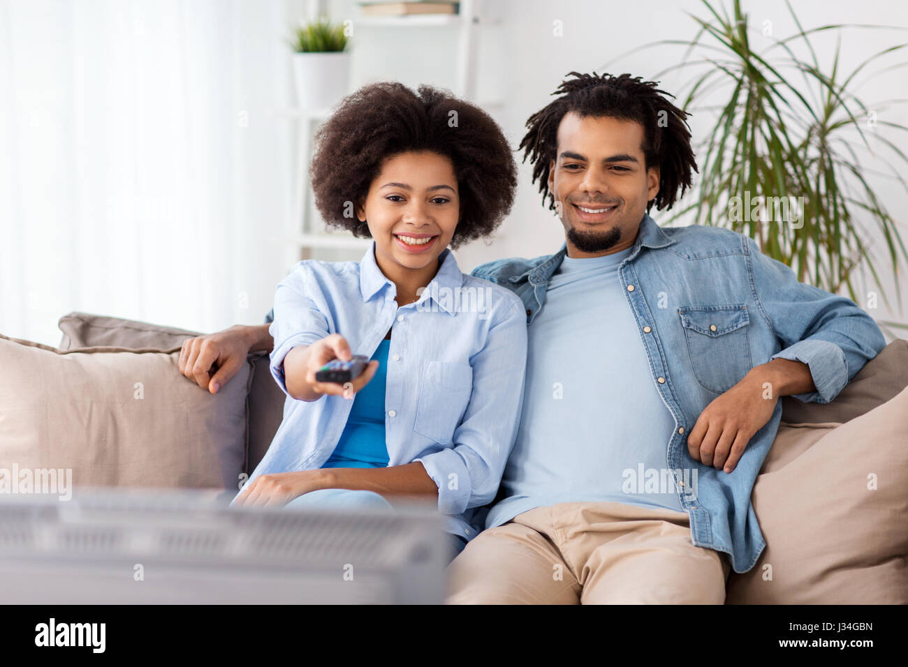 smiling couple with remote watching tv at home Stock Photo - Alamy