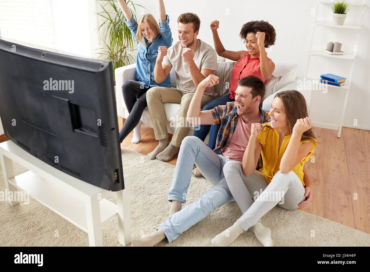 happy friends with remote watching tv at home Stock Photo - Alamy