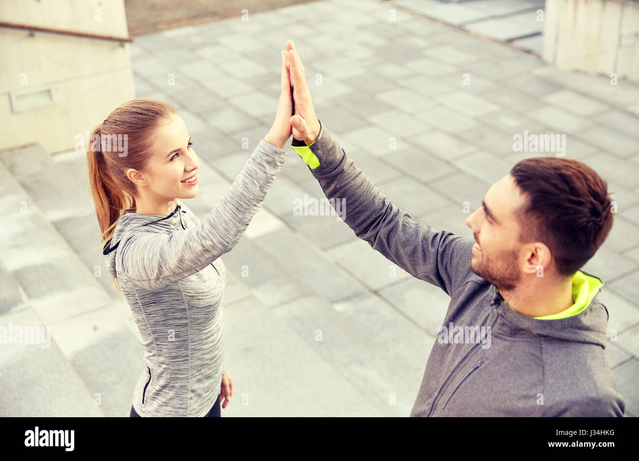 smiling couple making high five on city street Stock Photo - Alamy