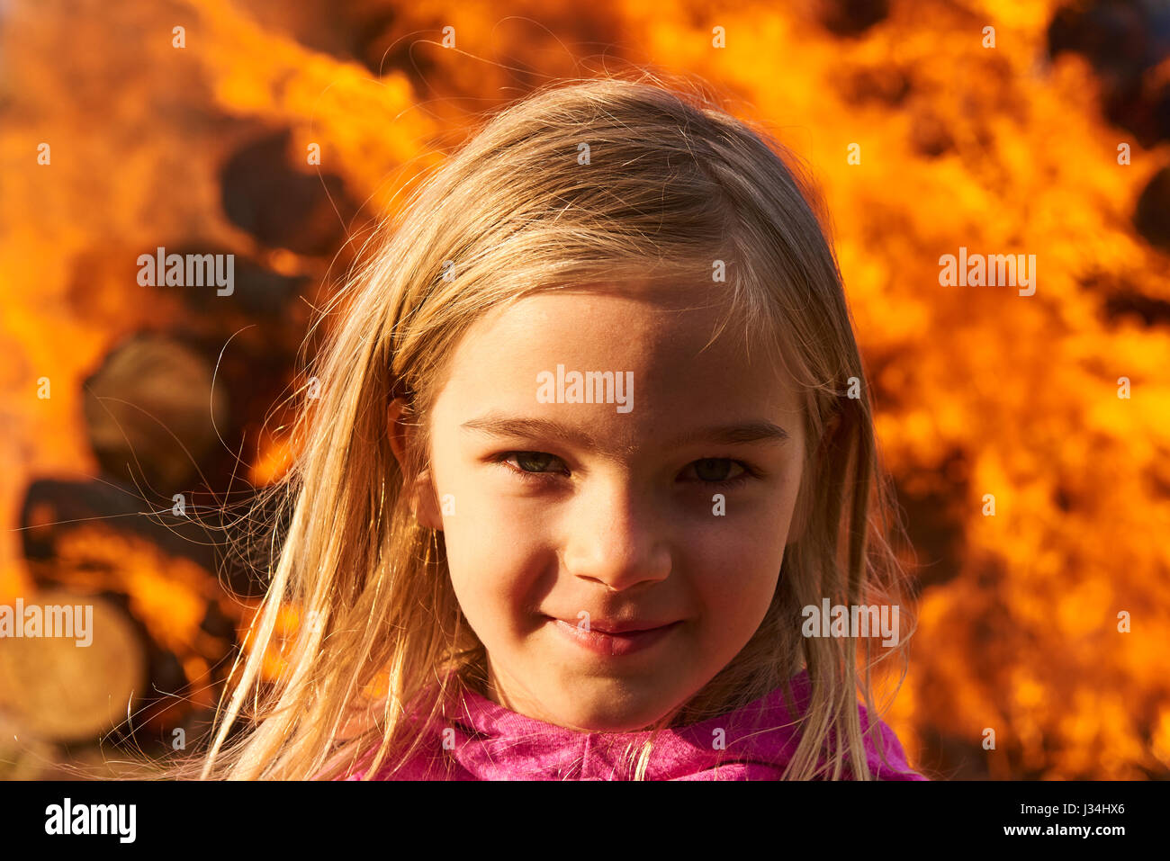 Portrait of child little blond girl with fire and flames background ...
