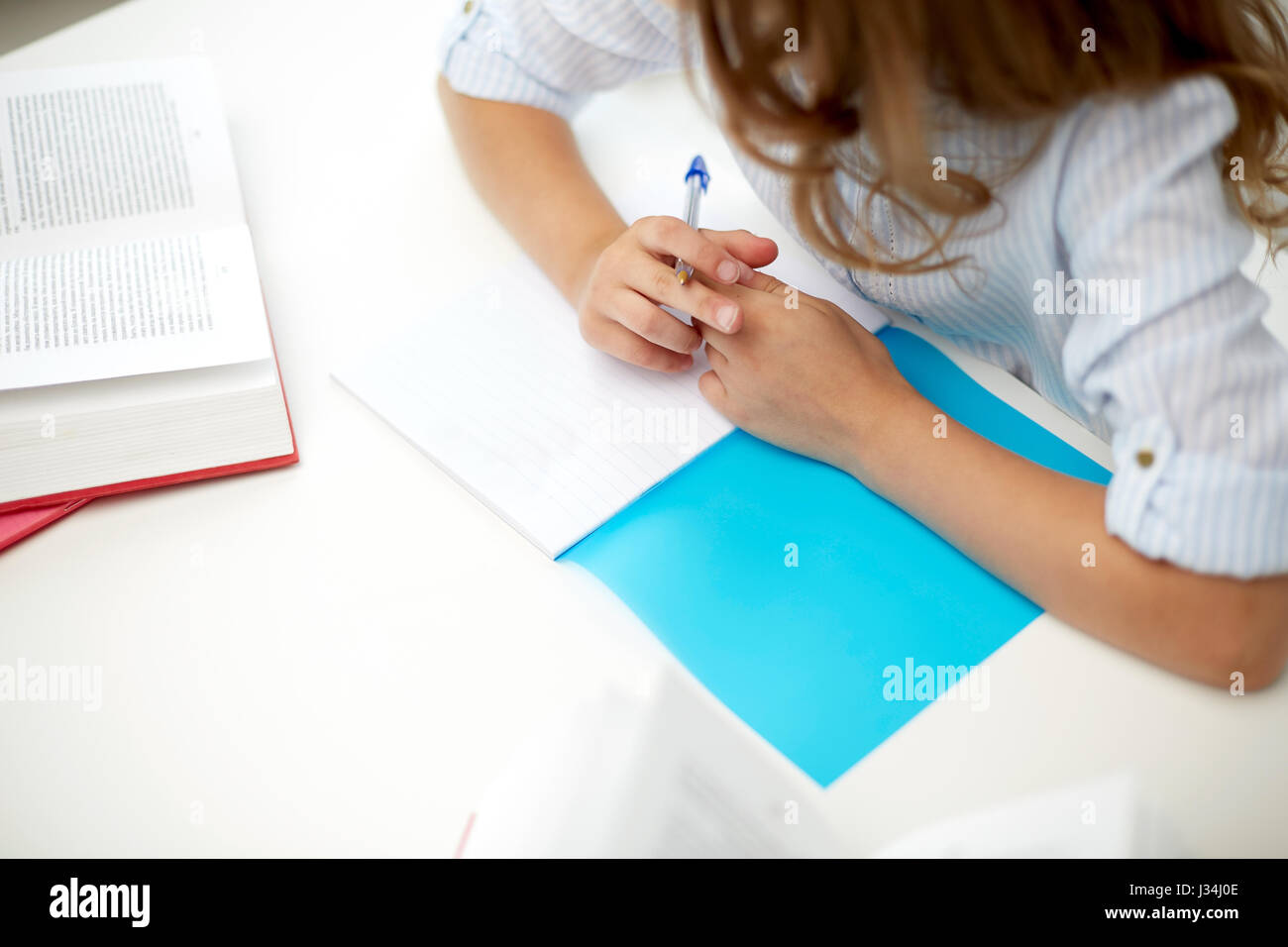 girl with book writing to notebook at school Stock Photo - Alamy