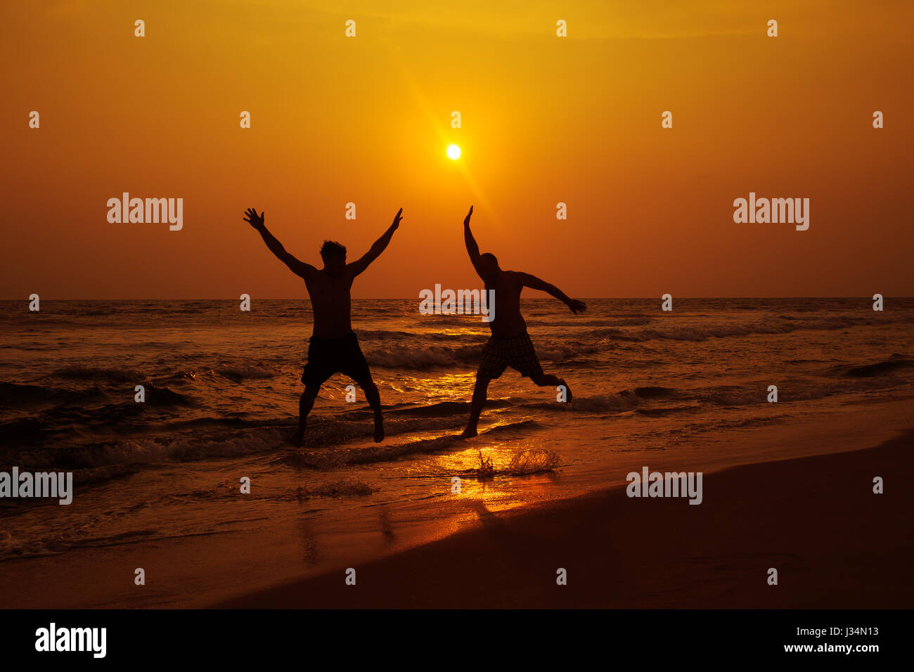 Two men are jumping on the beach. Sunset. The concept of a healthy ...