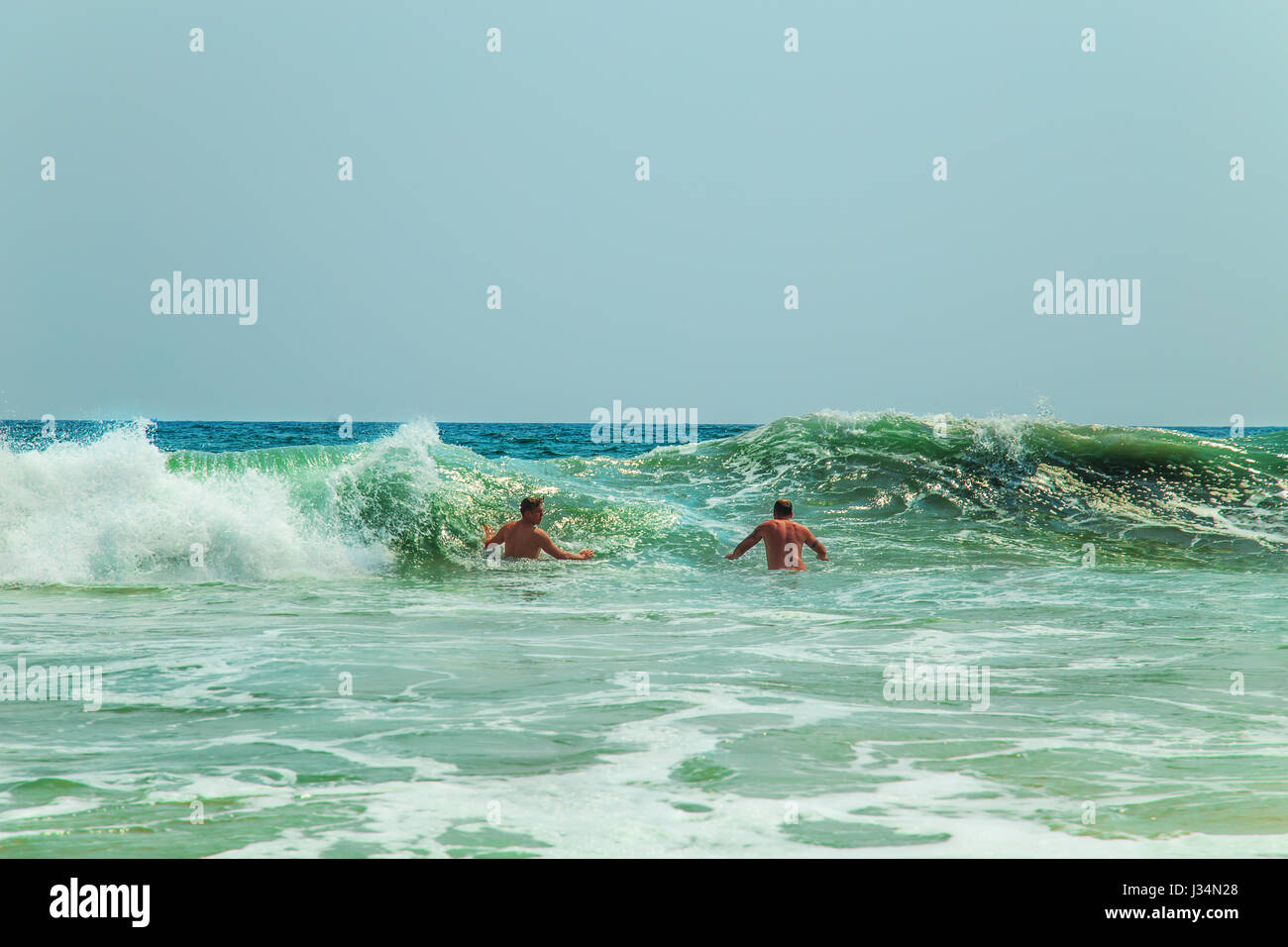 Two men dive into the waves of the Indian Ocean Stock Photo - Alamy