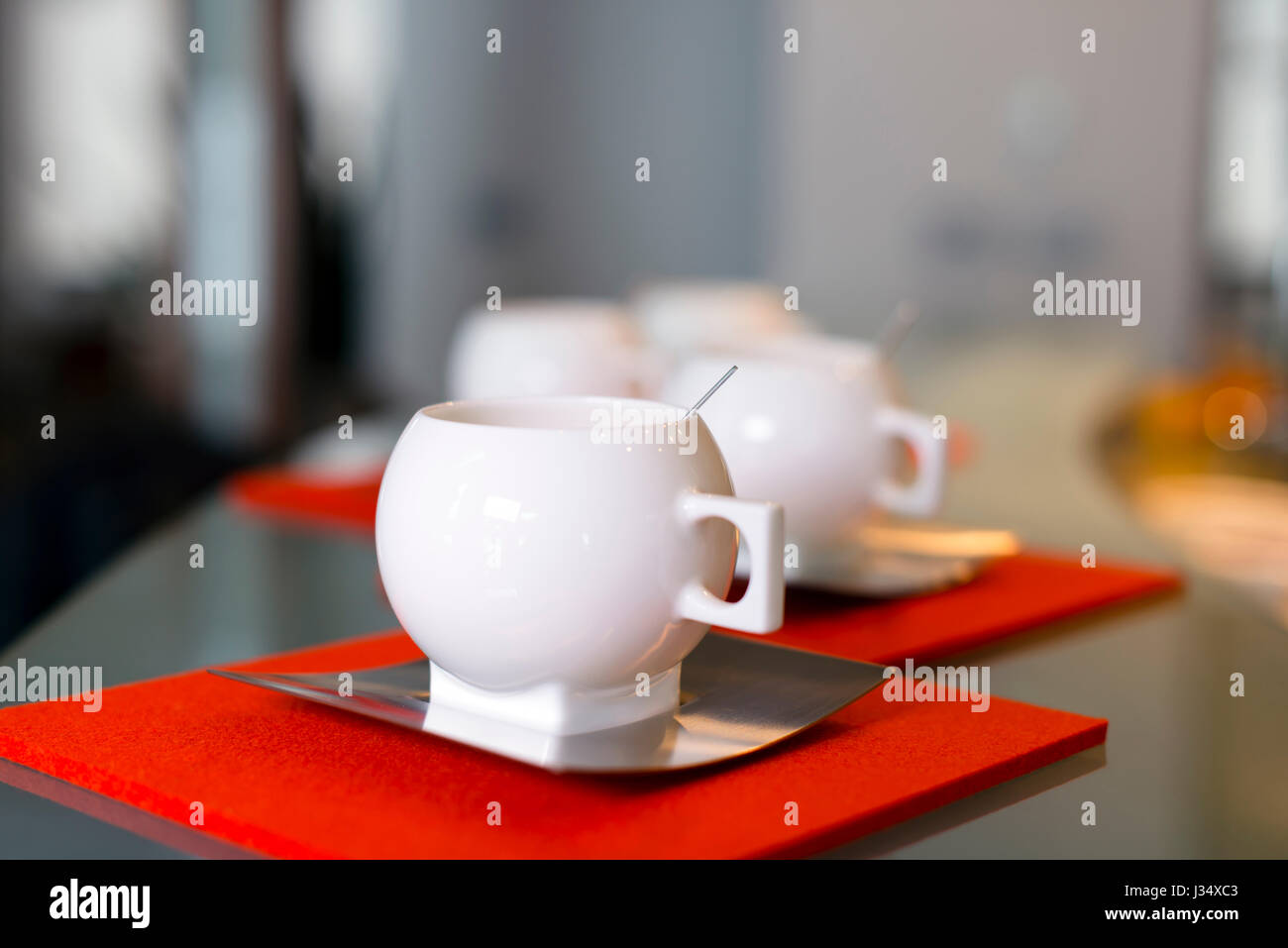 White porcelain modern cups with stainless steel saucers and spoons on ...