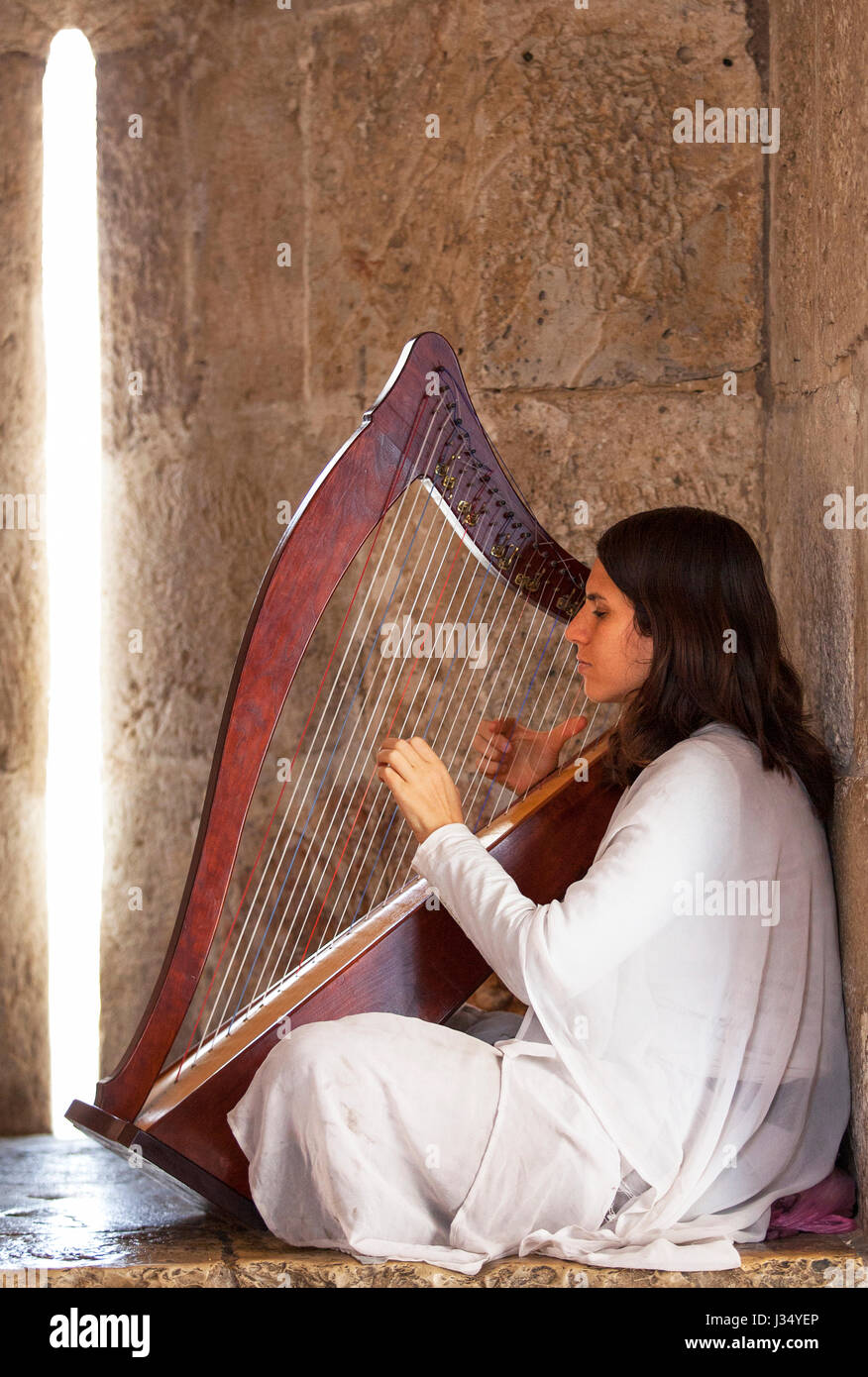 A young girl plays the harp inside the walls of the Jerusalem Old City ...