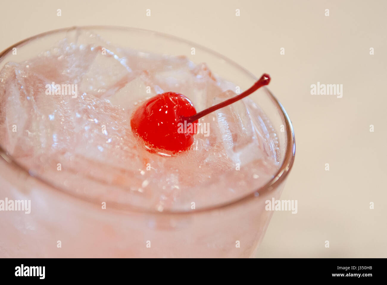 A closeup view of a summery cherry phosphate soda on ice, topped with a ...