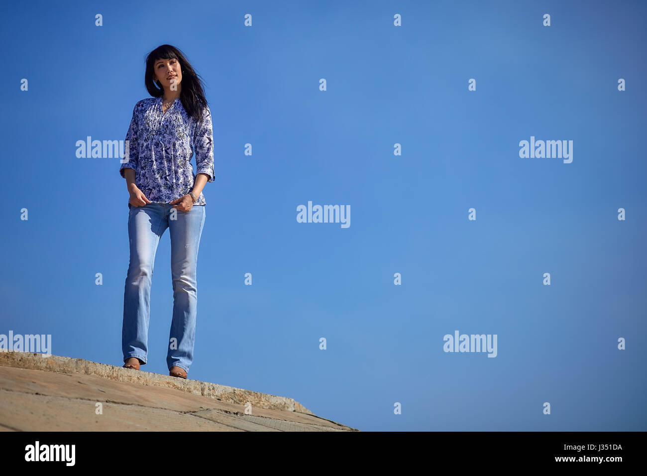 Beautiful asian girl stands in blue jeans against the blue sky Stock ...