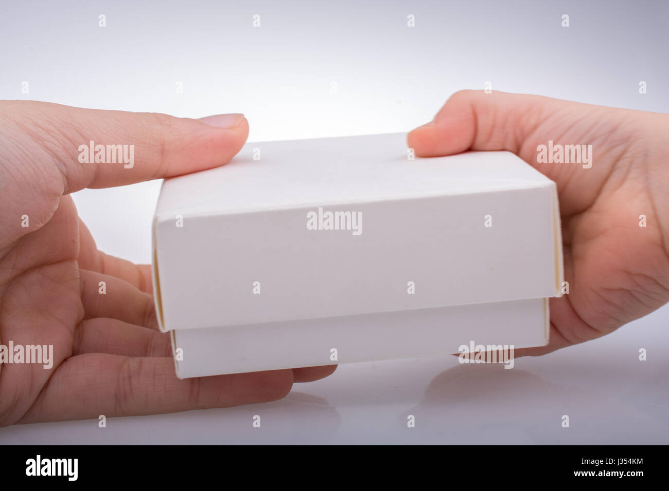 Hand giving a white gift box out Stock Photo - Alamy