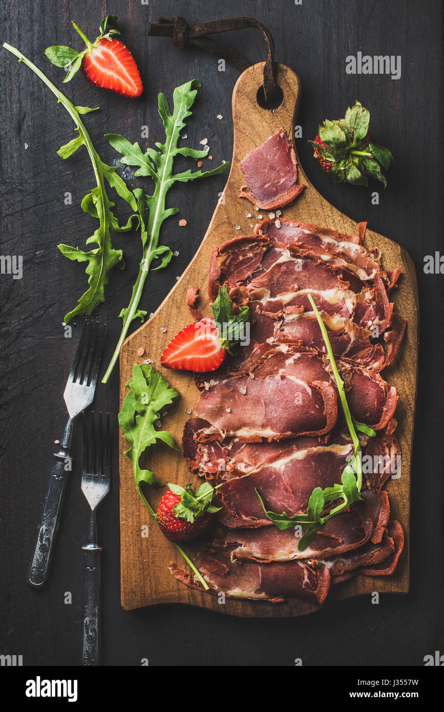 Turkish pastirma with strawberry and arugula on wooden board Stock ...