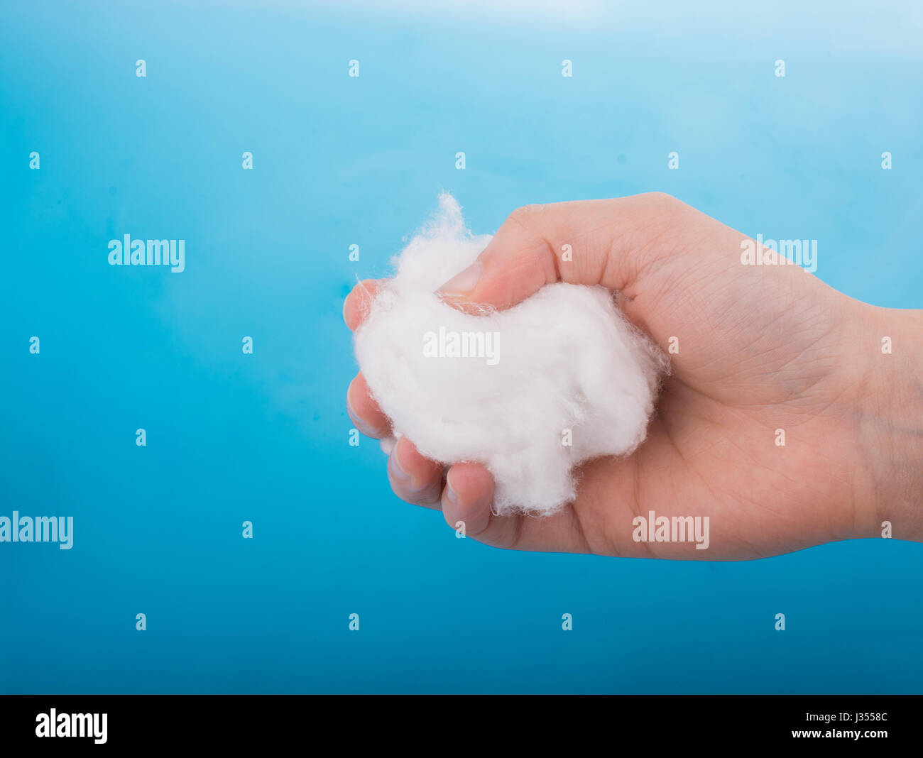 Hand holding some cotton in hand over blue water Stock Photo - Alamy