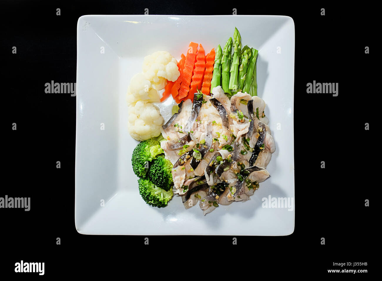 Slice steamed fish with braised leeks topping and spicy sauce in black ...