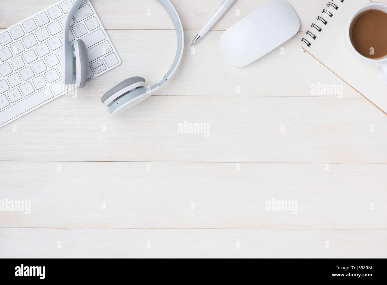 Notepad and computer keyboard on white table with headphone. View from ...