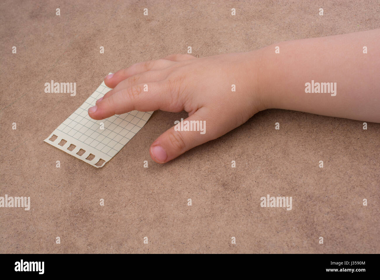 Hand holding a note paper on a brown background Stock Photo - Alamy
