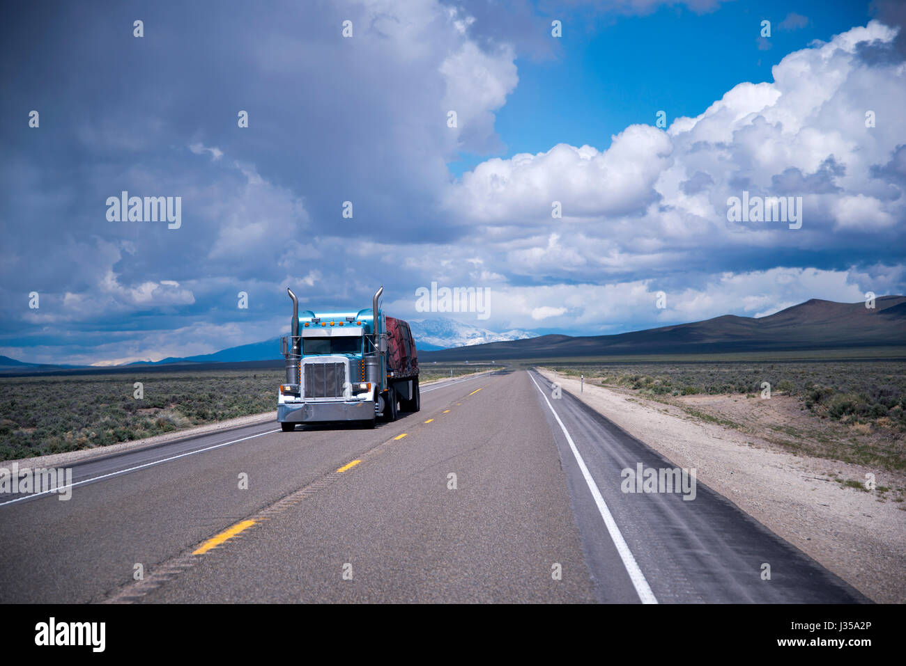 Classic bonneted American semi truck with cargo on flat bed trailer ...