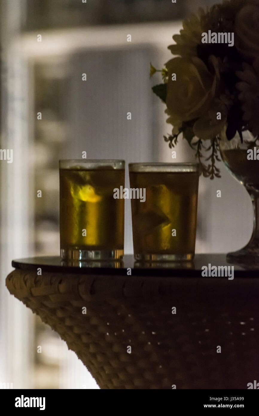 Two ice cold drinks standing on table at night in front of windows ...