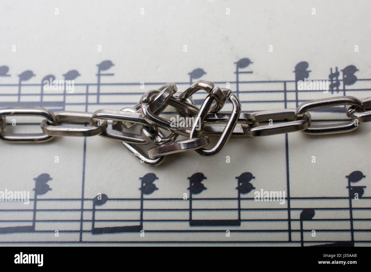 Metal chain placed on a paper with musical notes Stock Photo - Alamy