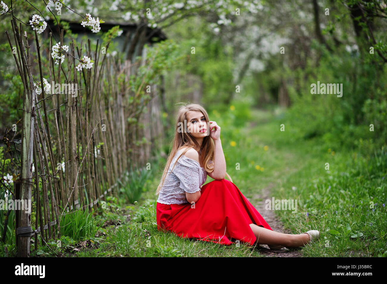 Portrait of sitting beautiful girl with red lips at spring blossom ...
