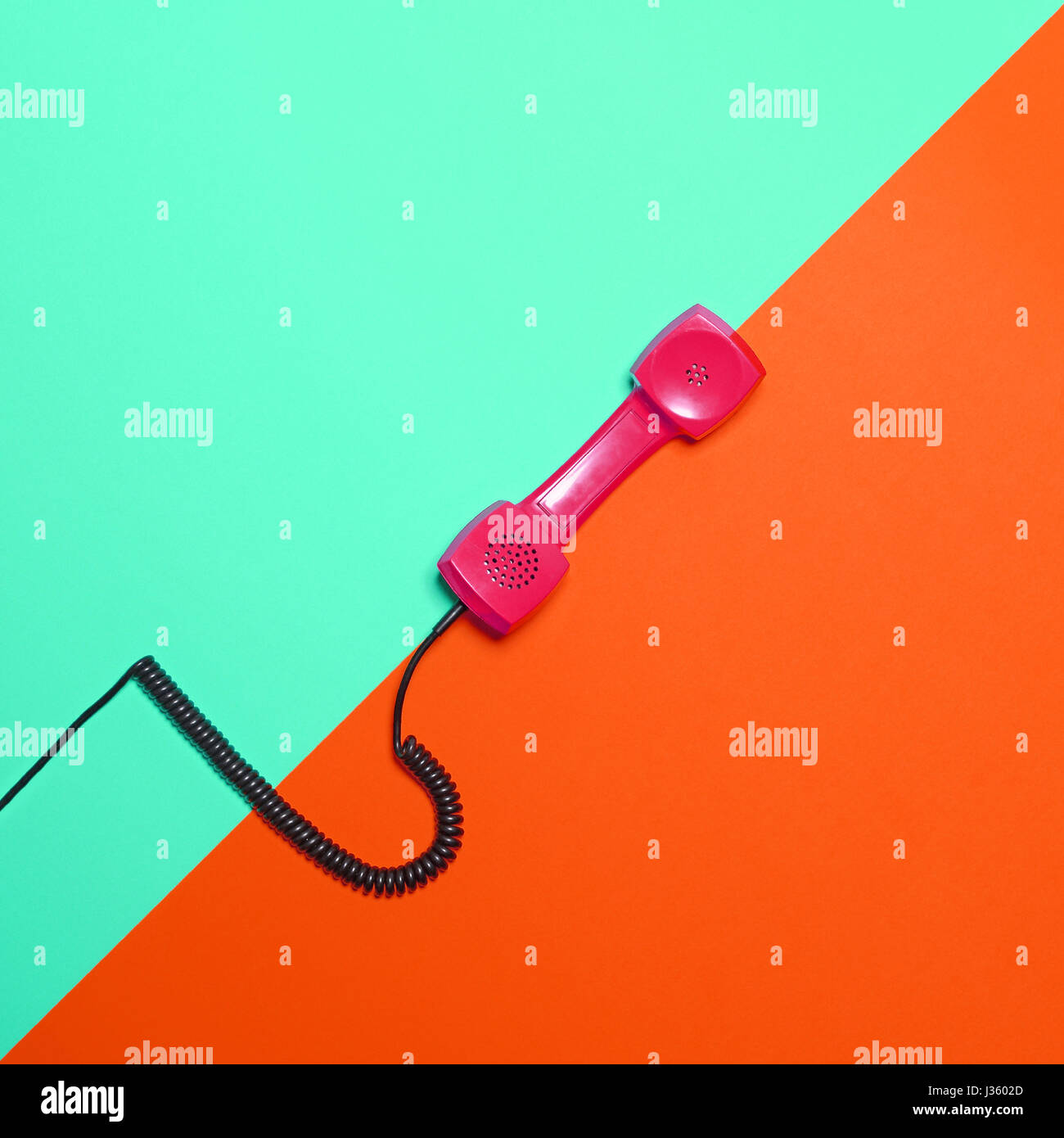 Retro orange telephone tube on striped blue and yellow background ...