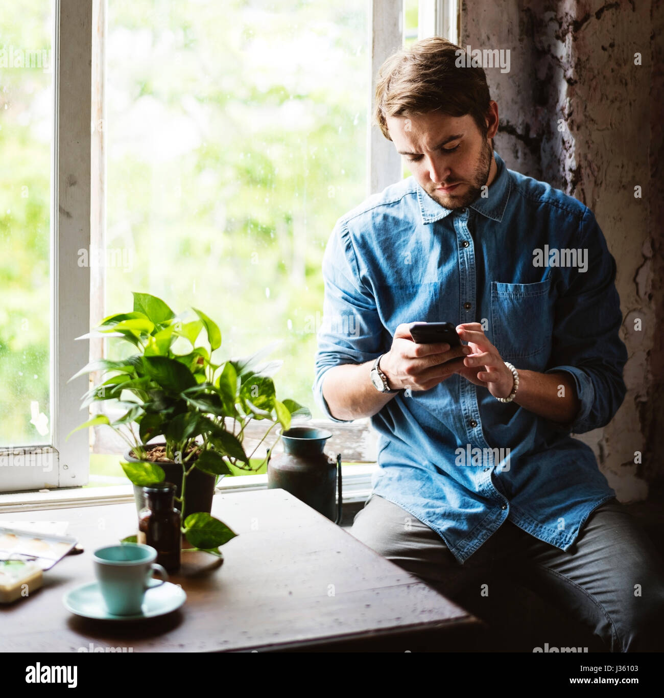 Man Using Mobile Phone Sitting by the Window Break Time Stock Photo - Alamy