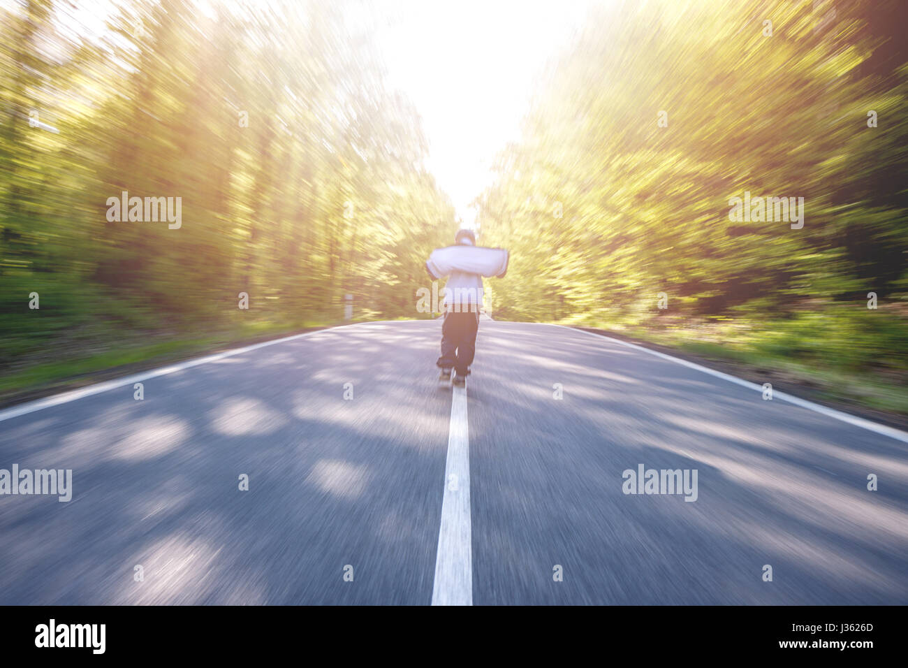 Panning shot of boy walking through a road in the middle of a forest ...