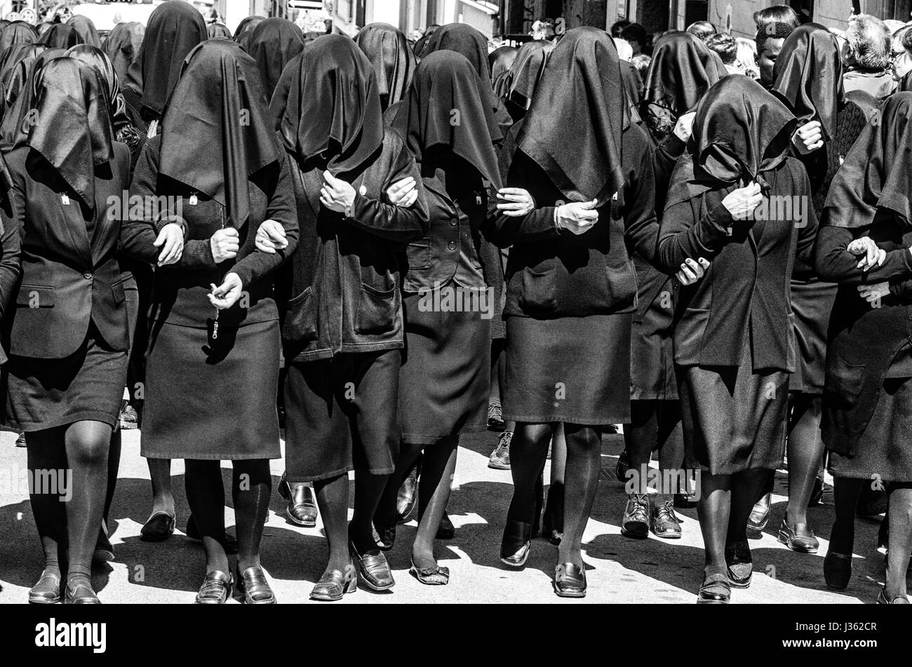 The women dressed in black parading arm in arm along the streets of ...