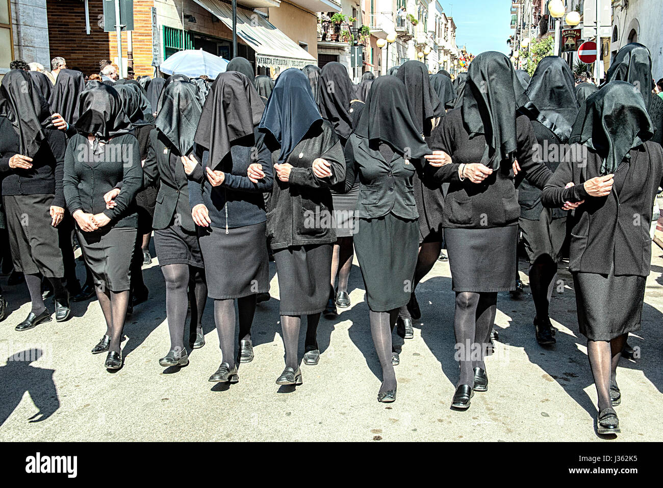 The women dressed in black parading arm in arm along the streets of ...