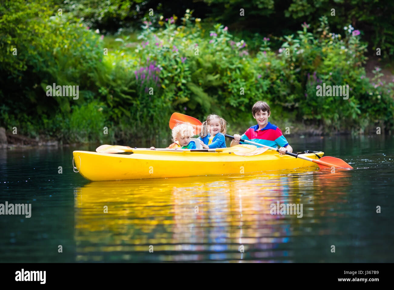 Happy family with three kids enjoying kayak ride on beautiful river ...