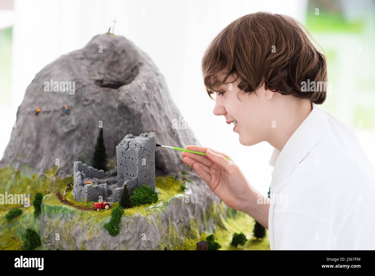 Teenager working on model building school project. Kids build miniature ...