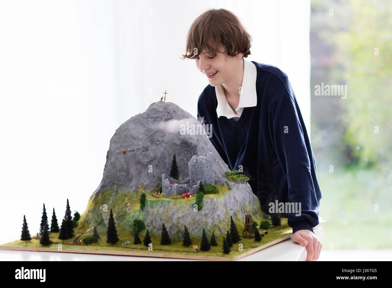 Teenager working on model building school project. Kids build miniature ...